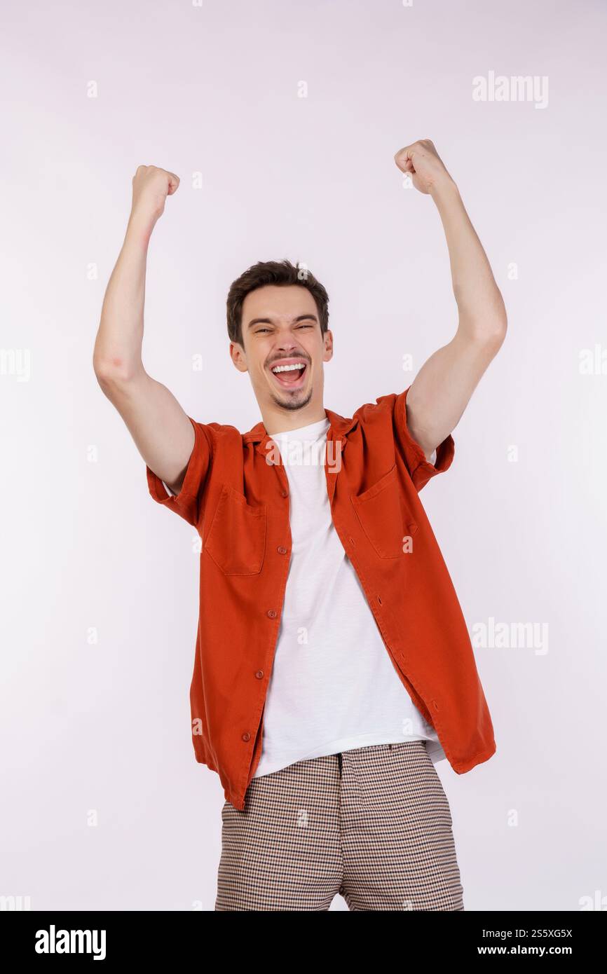 Portrait of happy joyful young man standing doing winner gesture ...