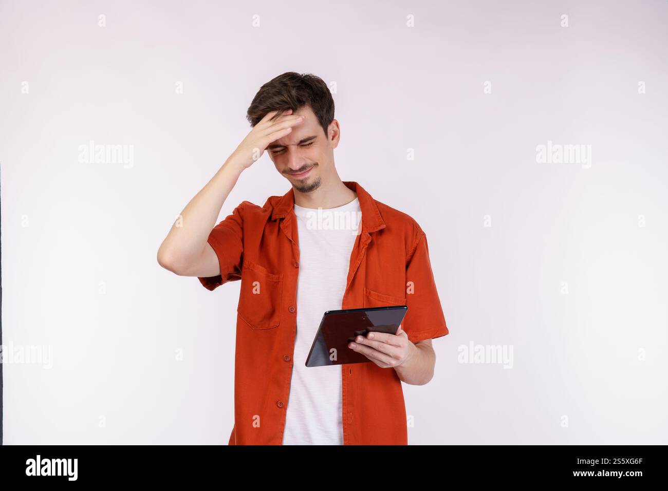 Portrait of stressed man using tablet standing isolated over white ...