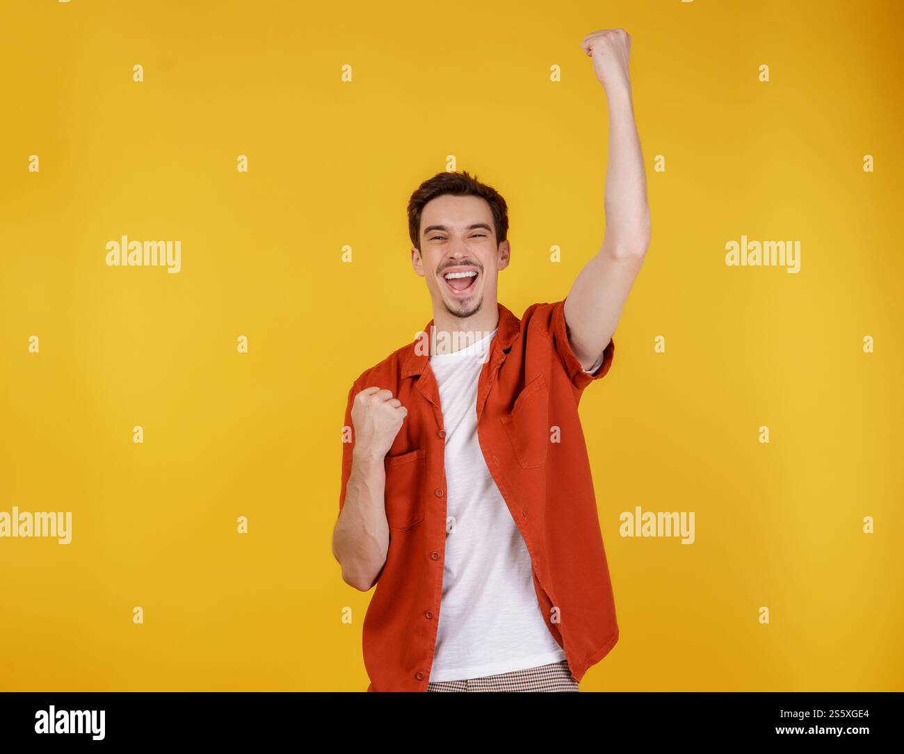 Portrait of happy joyful young man standing doing winner gesture ...