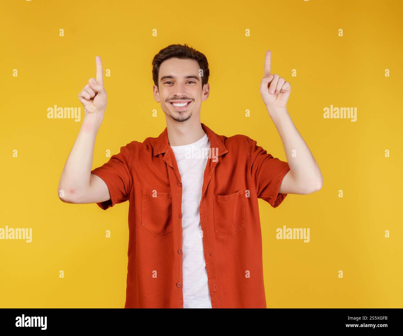 Portrait of young man pointing fingers at copy space isolated on yellow ...