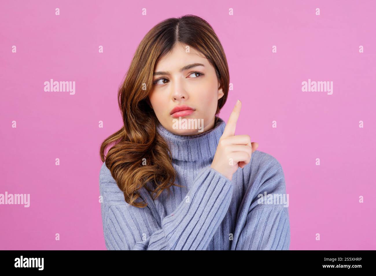 Portrait of young woman pointing finger up and thinking isolated over ...