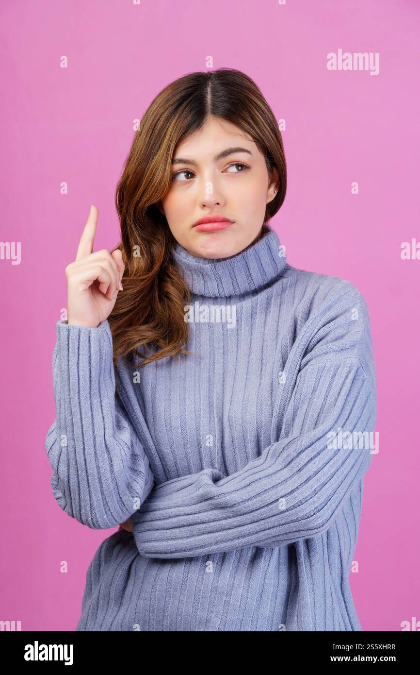 Portrait of young woman pointing finger up and thinking isolated over ...