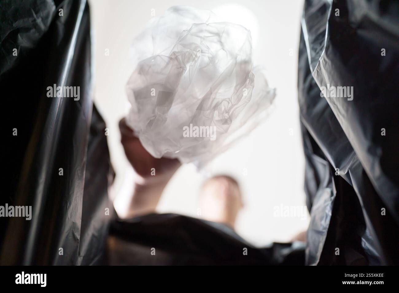 Image from inside black recycling bag of man throwing empty plastic ...