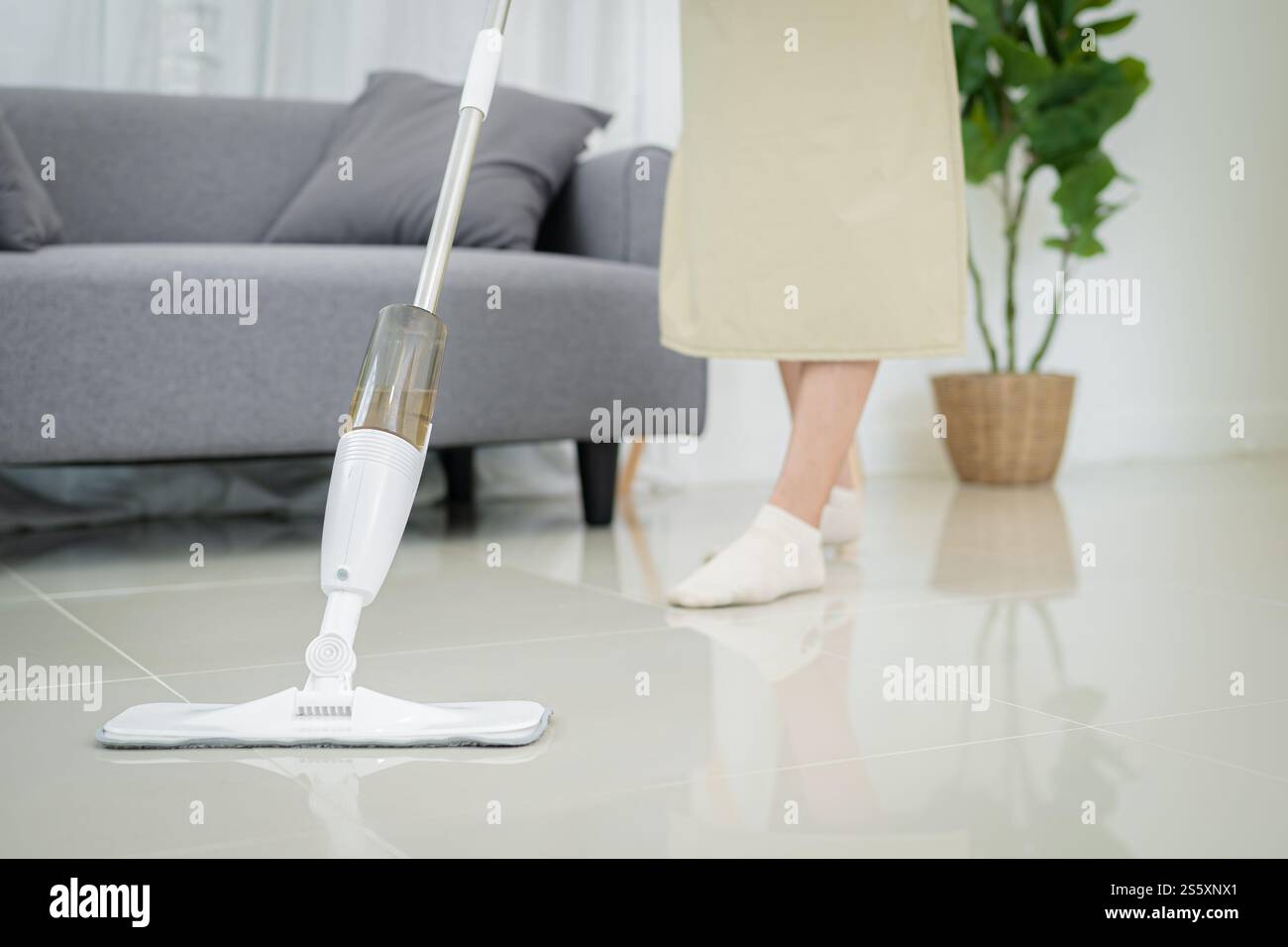 Beautiful Asian woman cleaning living room in house Sweeping the floor using microfiber wet mop ...