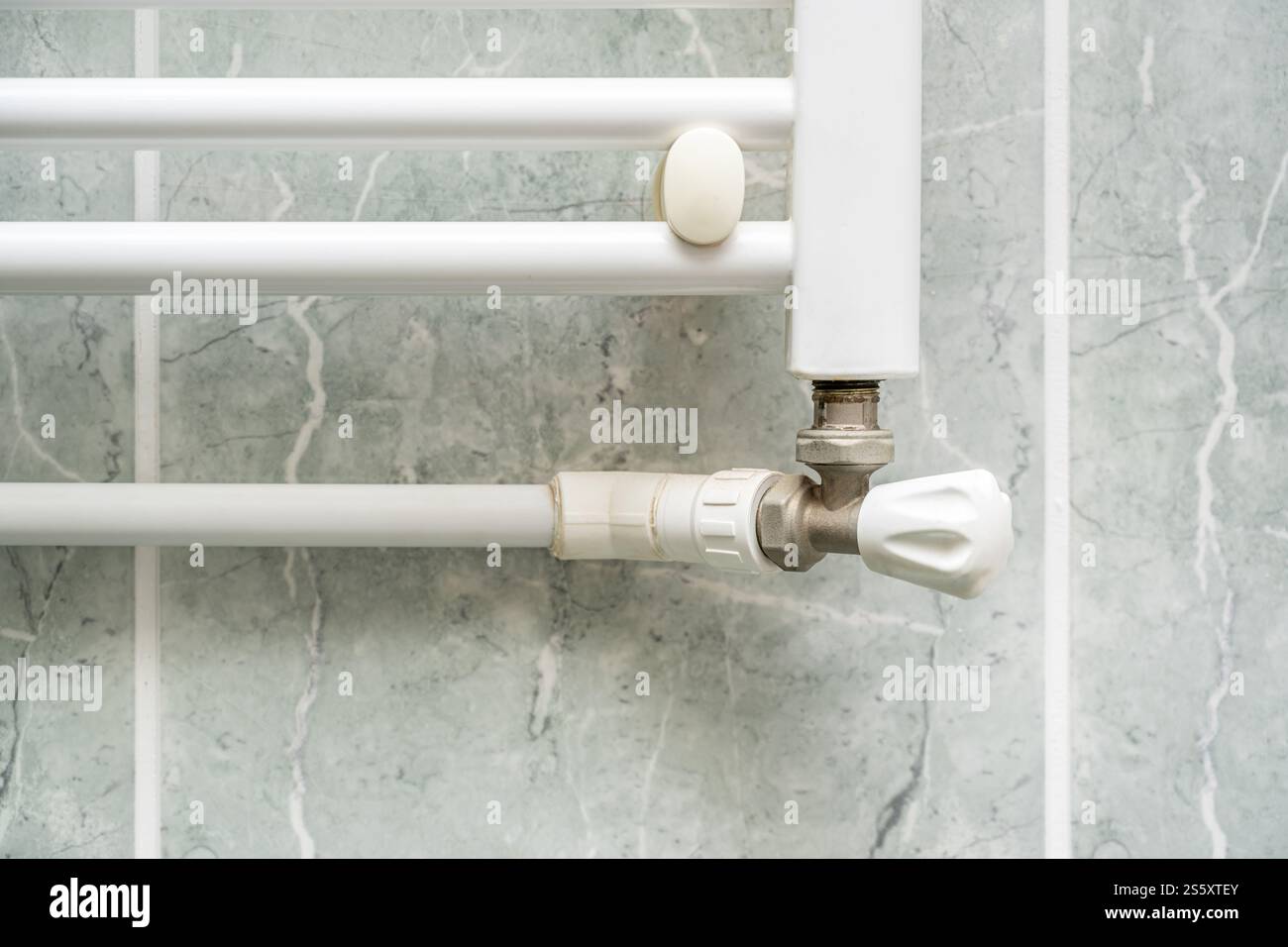 White radiator hung on the wall in a bathroom with green ceramic tiles ...