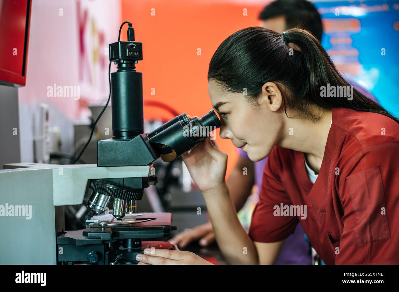 Asian young female farmer looking through a microscope in a laboratory. Modern technologies in ...