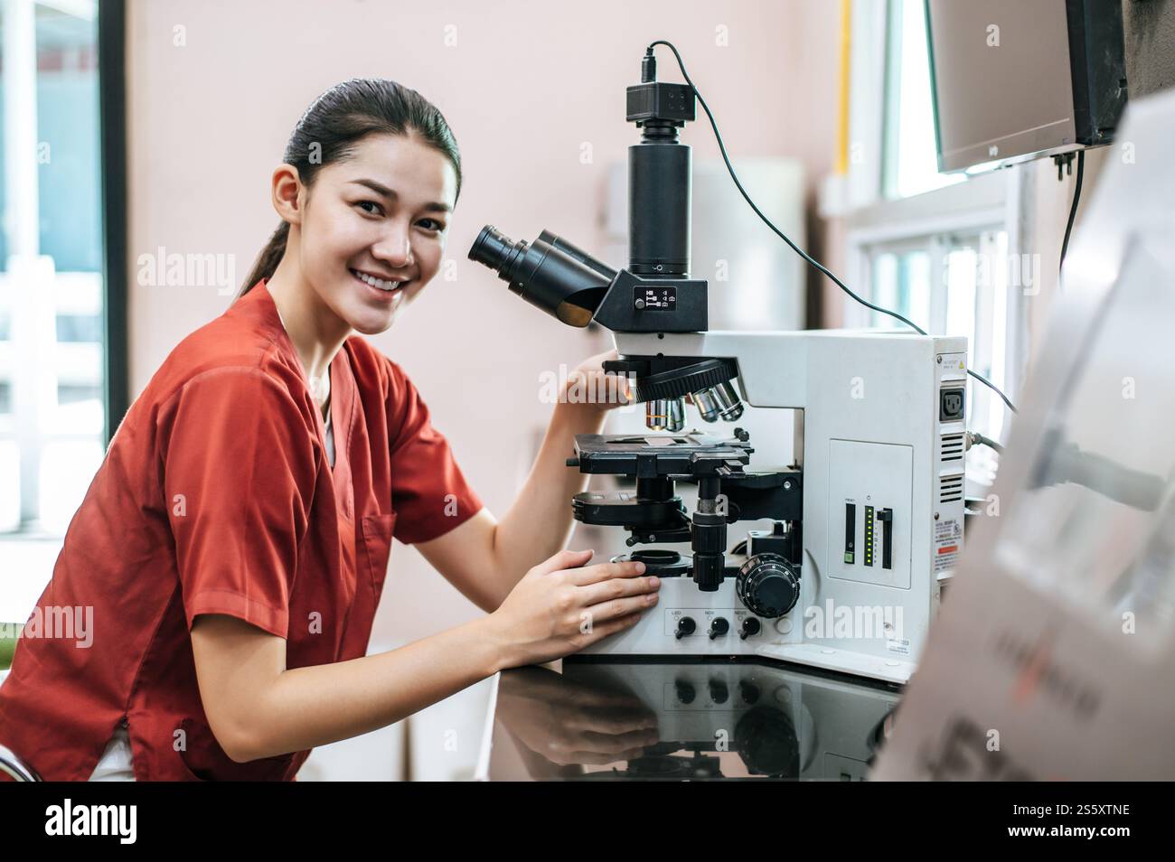 Asian young female farmer looking through a microscope in a laboratory. Modern technologies in ...