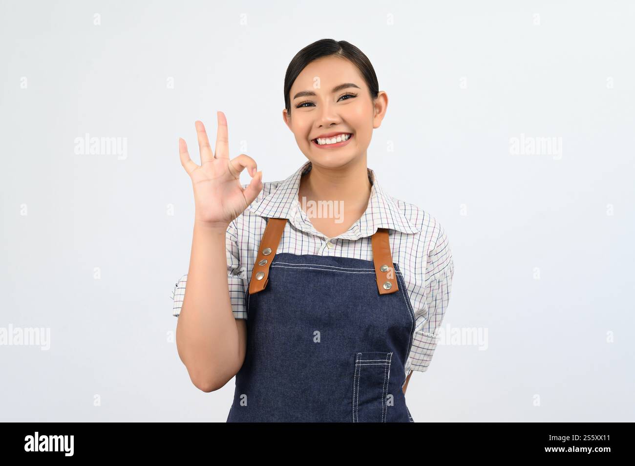 Portrait Asian young woman in waitress uniform and apron showing finger ...