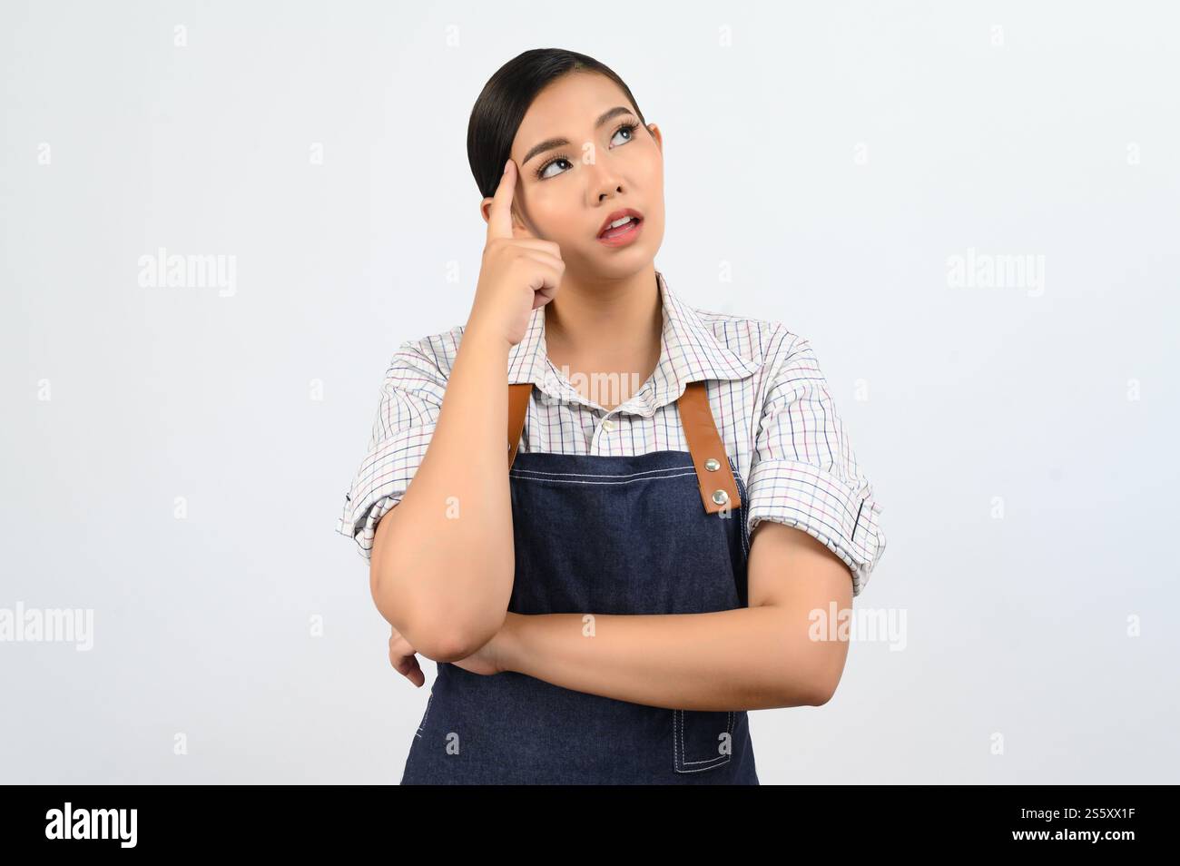Portrait of young asian woman in waitress costume standing and thinking ...