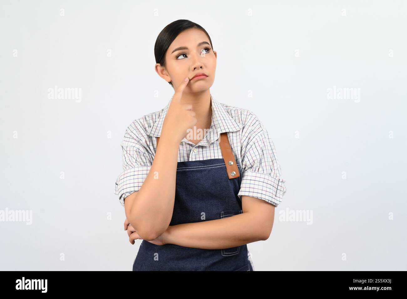 Portrait of young asian woman in waitress costume standing and thinking ...