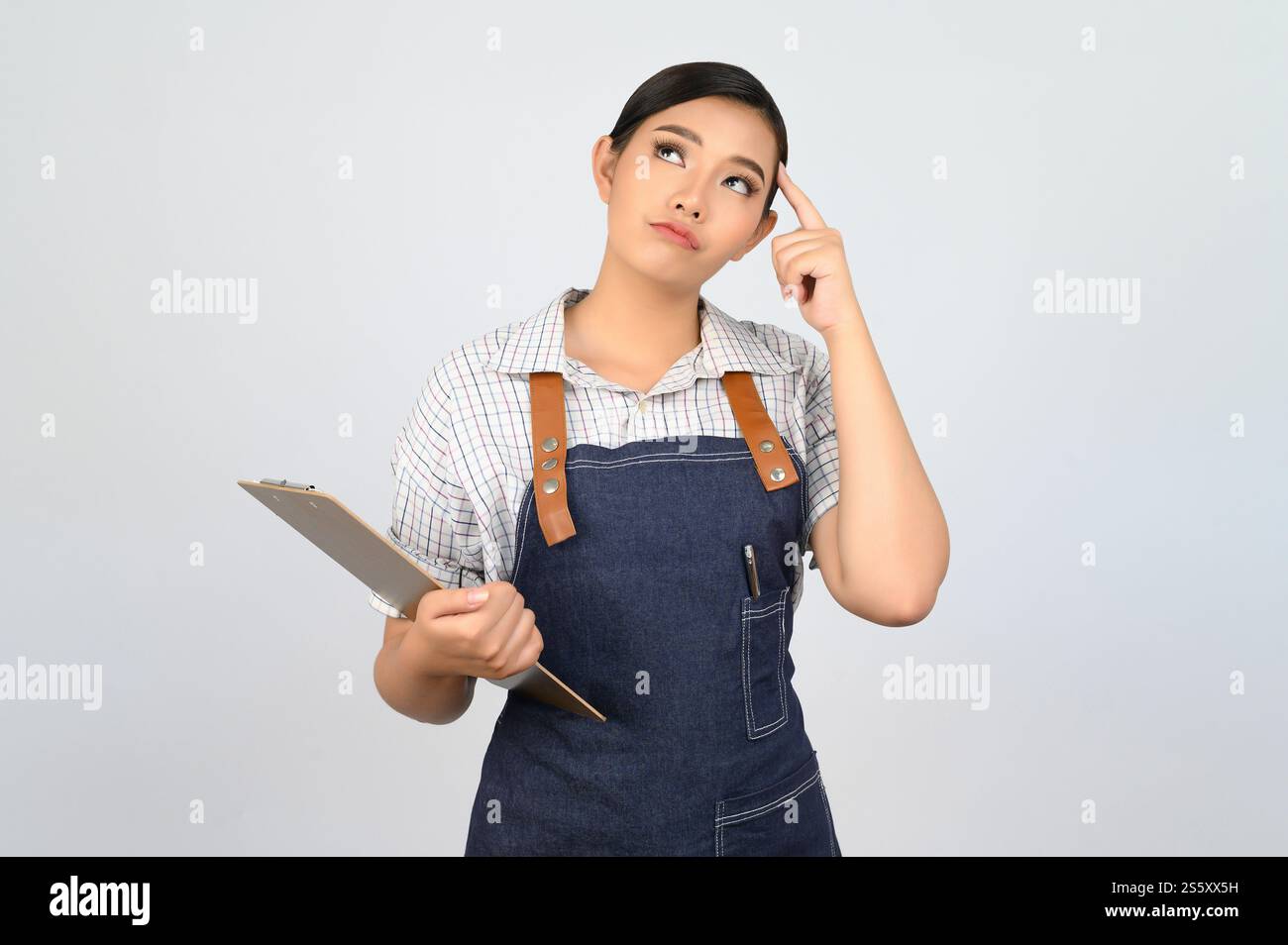 Portrait of young asian woman in waitress uniform holding clipboard and ...