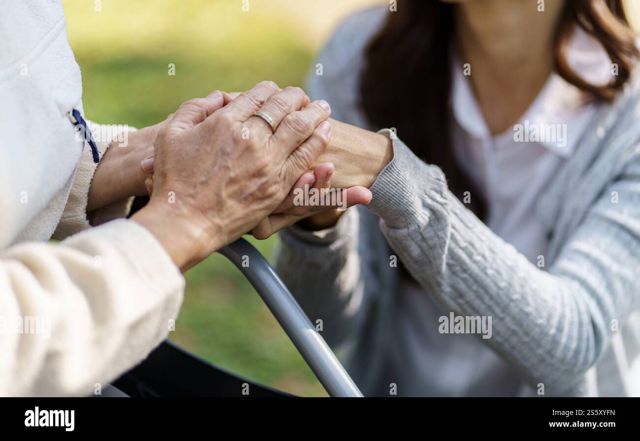 Family relationship Asian senior woman in wheelchair with happy daughter holding caregiver for a ...