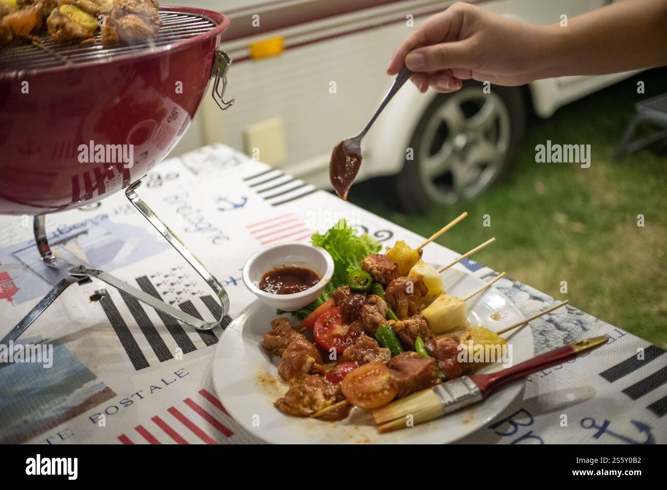 Friends making barbecue BBQ grilling over a hot fire in the nature ...