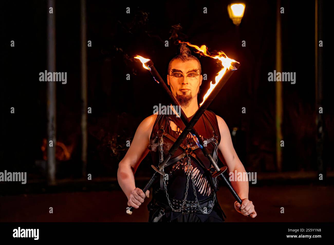 Fire artist performing with flaming swords at night, creating a ...