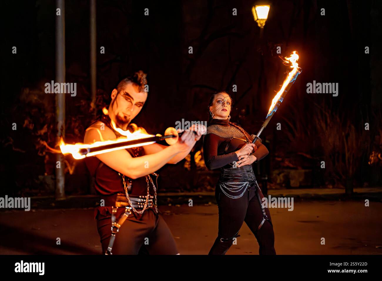 Two fire dancers performing with burning swords in a night show ...