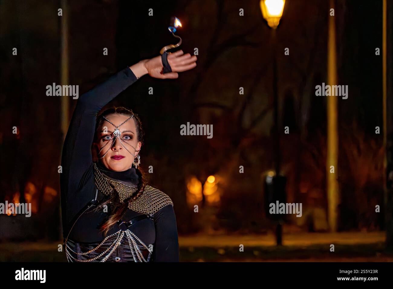 Fire artist performing with a flaming torch in a night urban setting ...