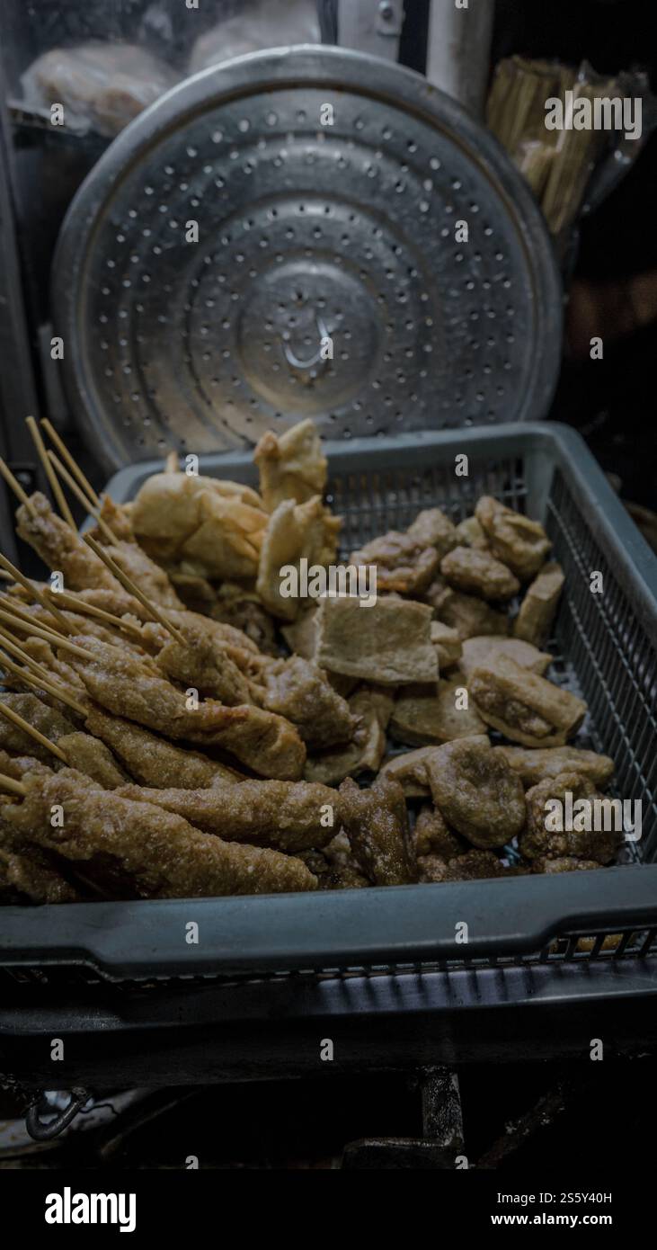 A basket filled with various fried street food items, including skewers ...