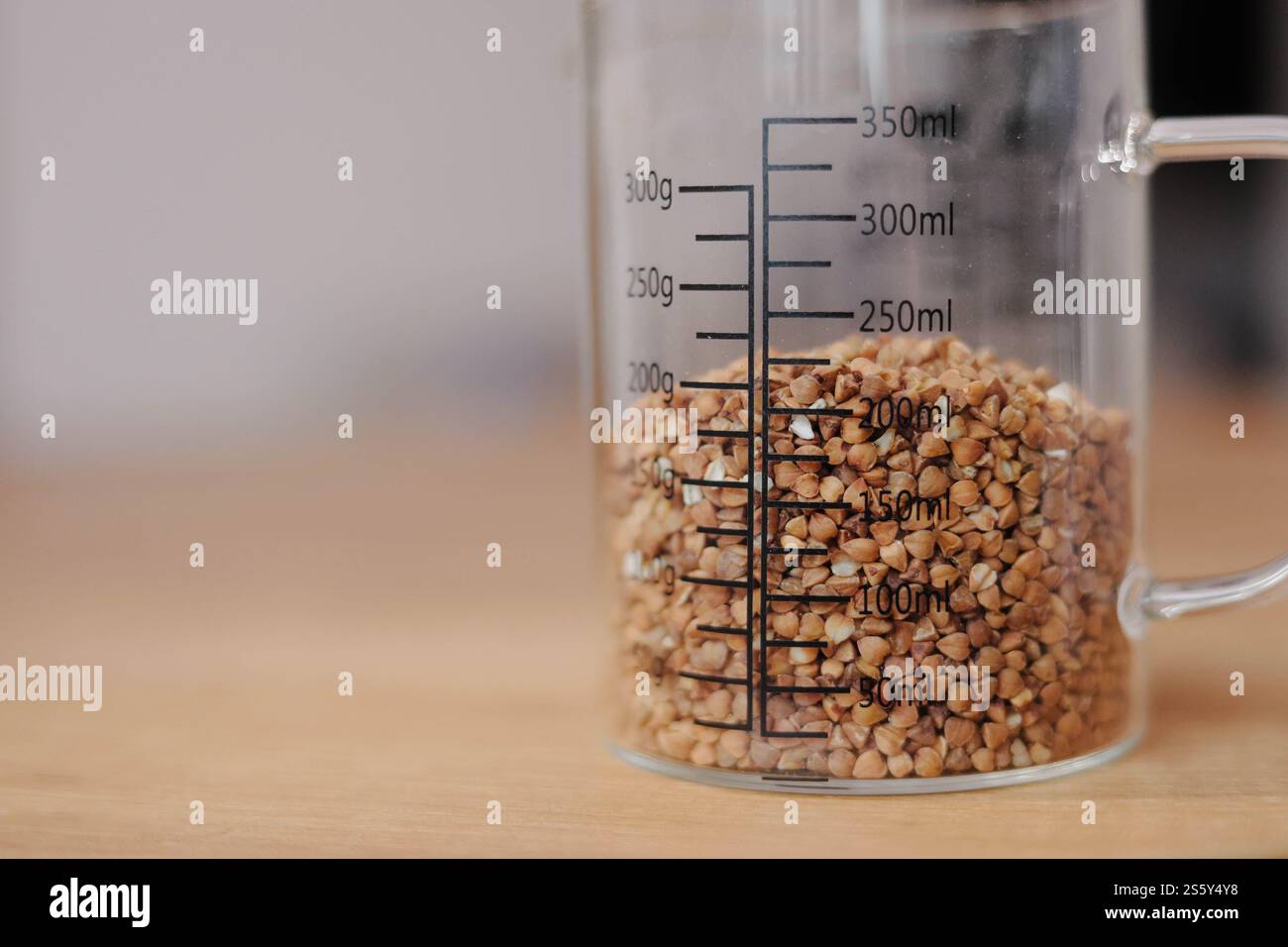 Buckwheat grains pouring into glass storage jar in the kitchen, copy ...