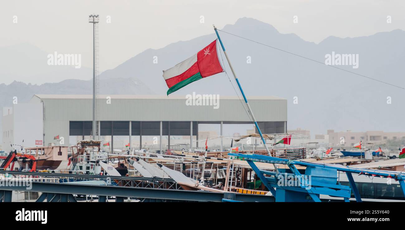 Khasab, Oman - January 1, 2025: The Omani flag waves proudly over a ...