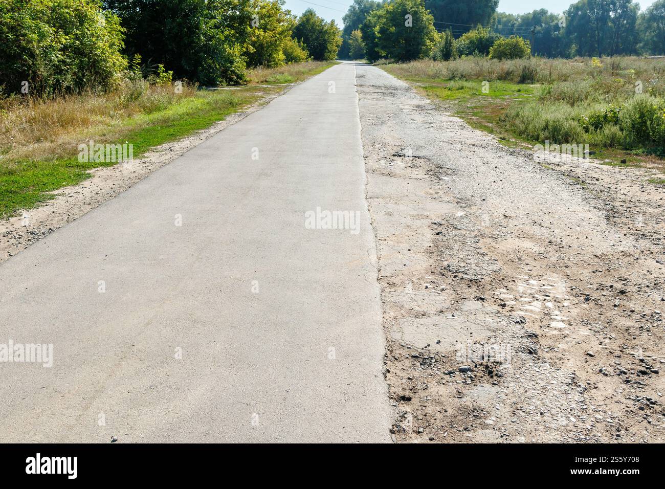 A local road with two lanes, half of which is covered with new asphalt ...