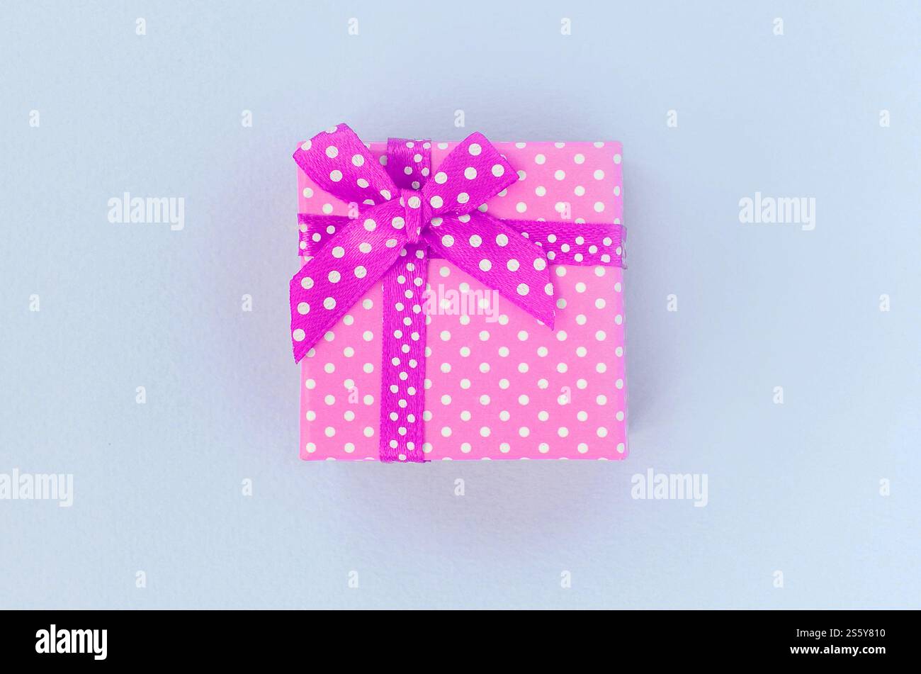 Small purple gift box with ribbon lies on a violet background ...