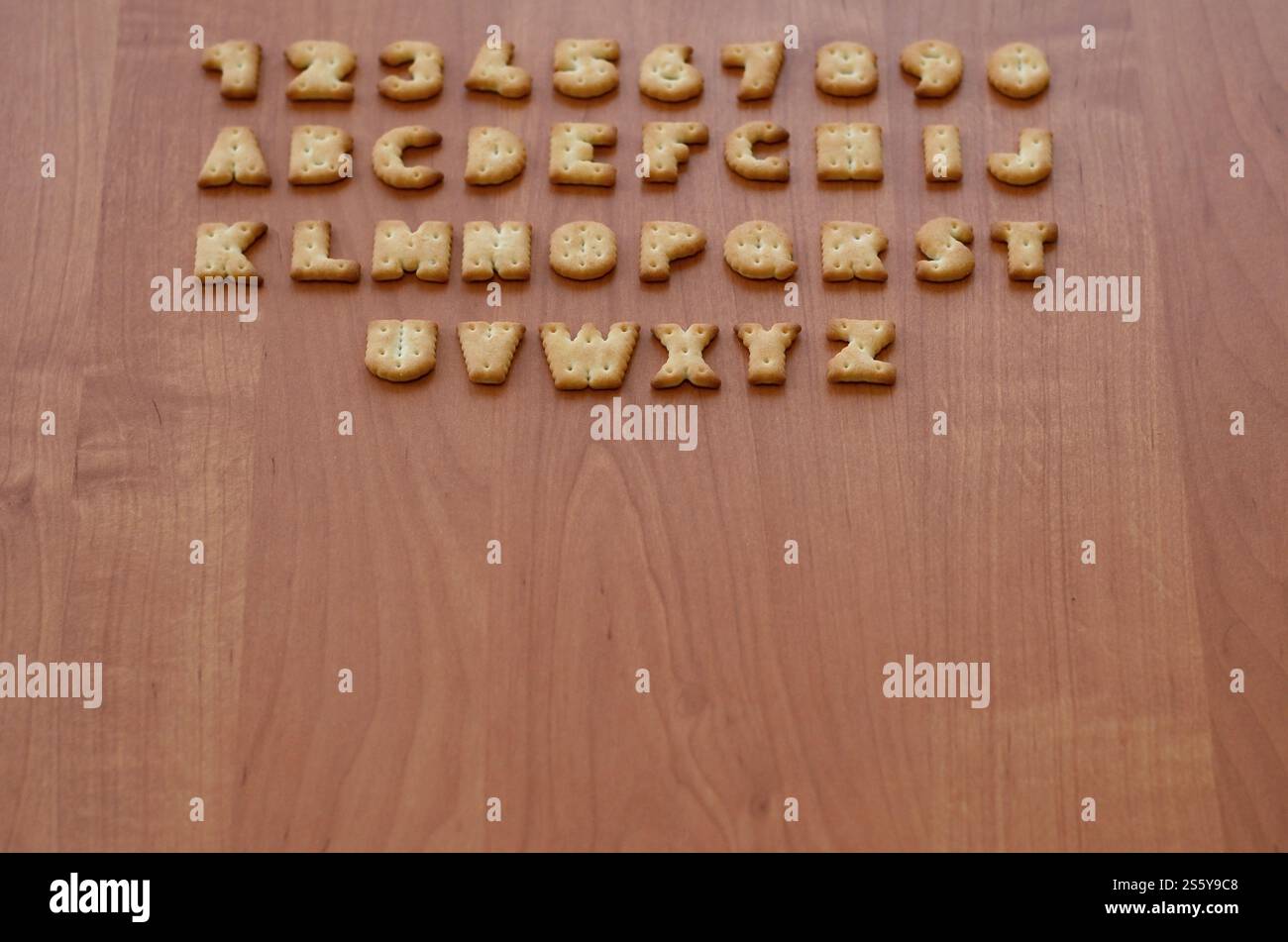 Letters of salty crackers lay on a wooden brown surface in the order ...