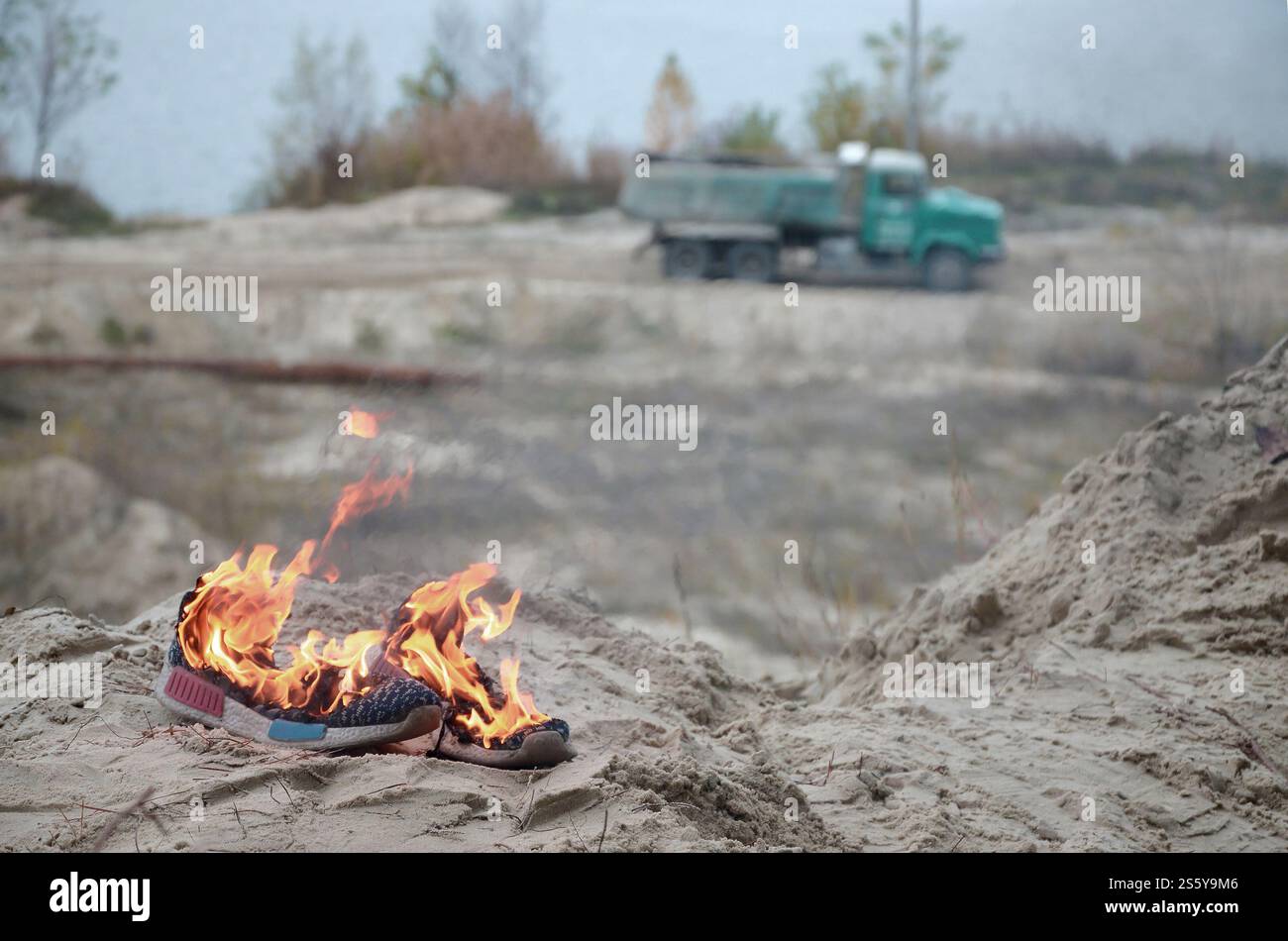 Burning sports sneakers or gym shoes on fire stand on sandy beach coast ...