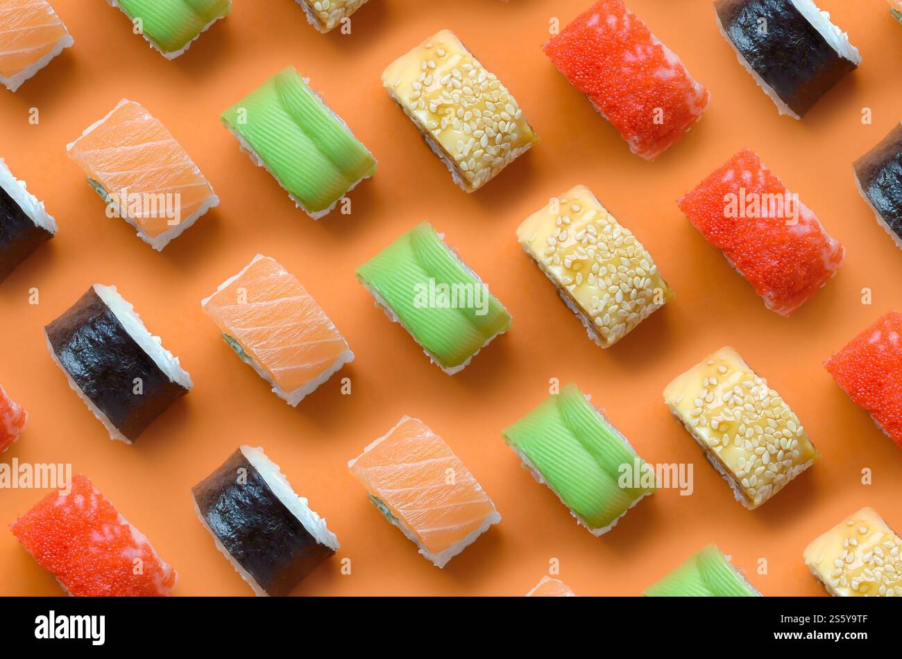 Different types of asian sushi rolls on orange background close up ...