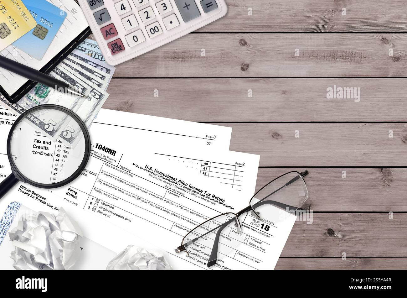 IRS form 1040NR Nonresident Alien Income tax return lies on flat lay office table and ready to ...