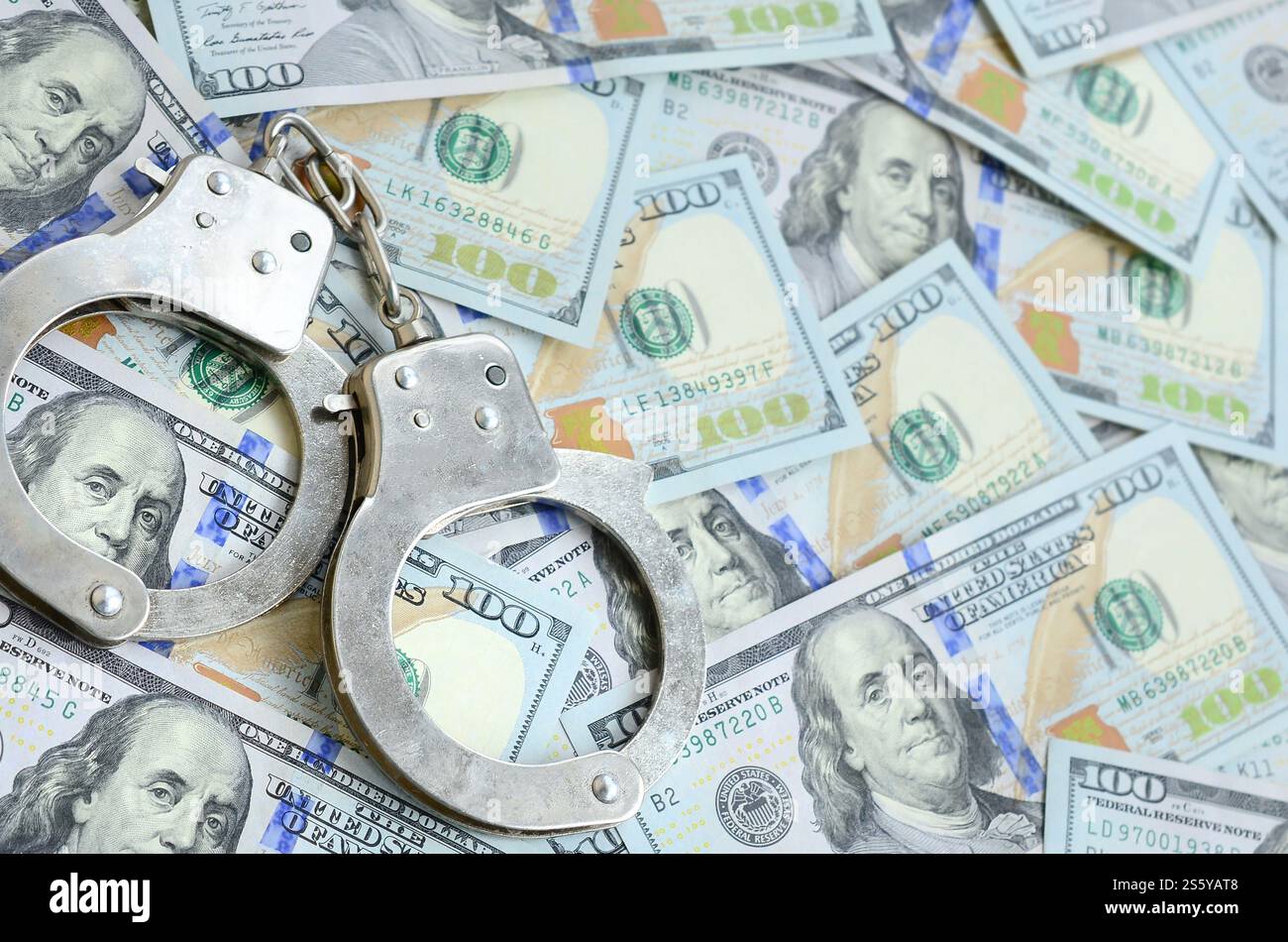 Silver police handcuffs lies on a many dollar bills. Silver police ...
