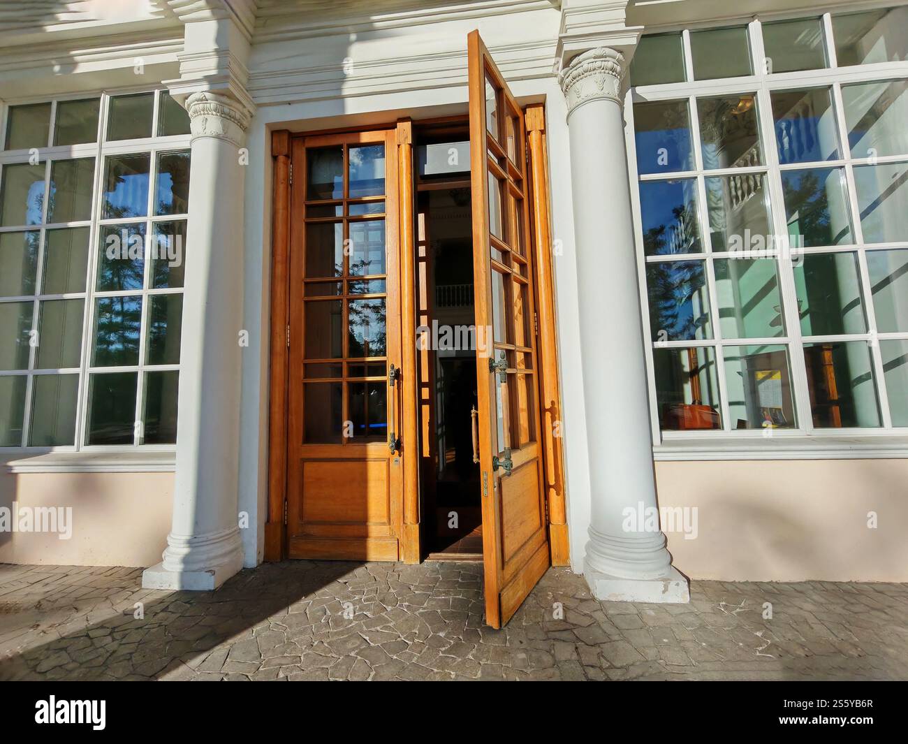 A grand wooden door set in a neoclassical facade with white columns and ...