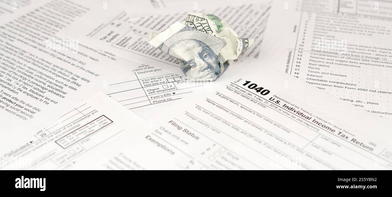 1040 Individual income tax return form and crumpled hundred dollar bill ...