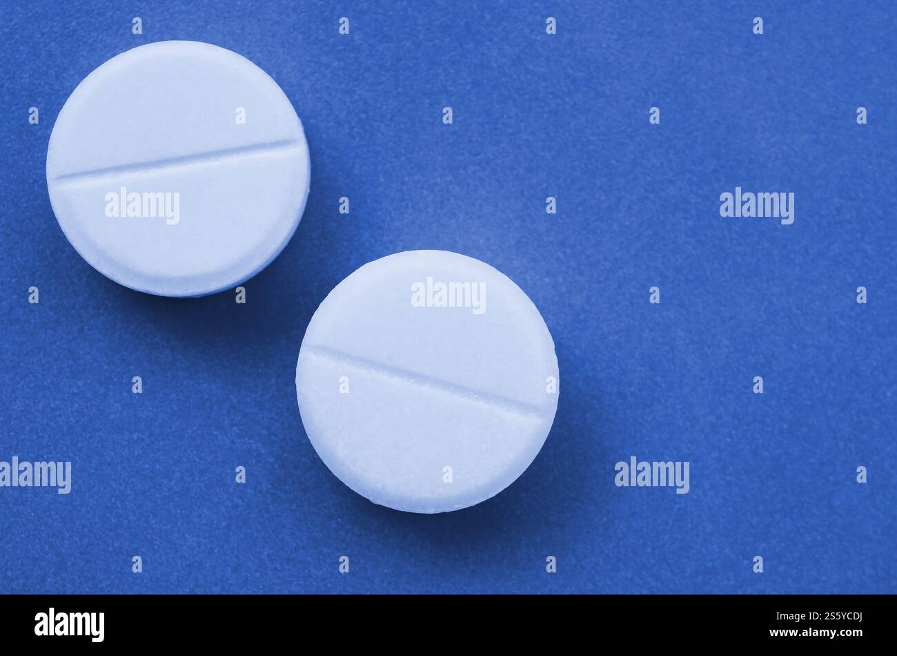 A few white tablets lie on a bright phantom classic blue color ...