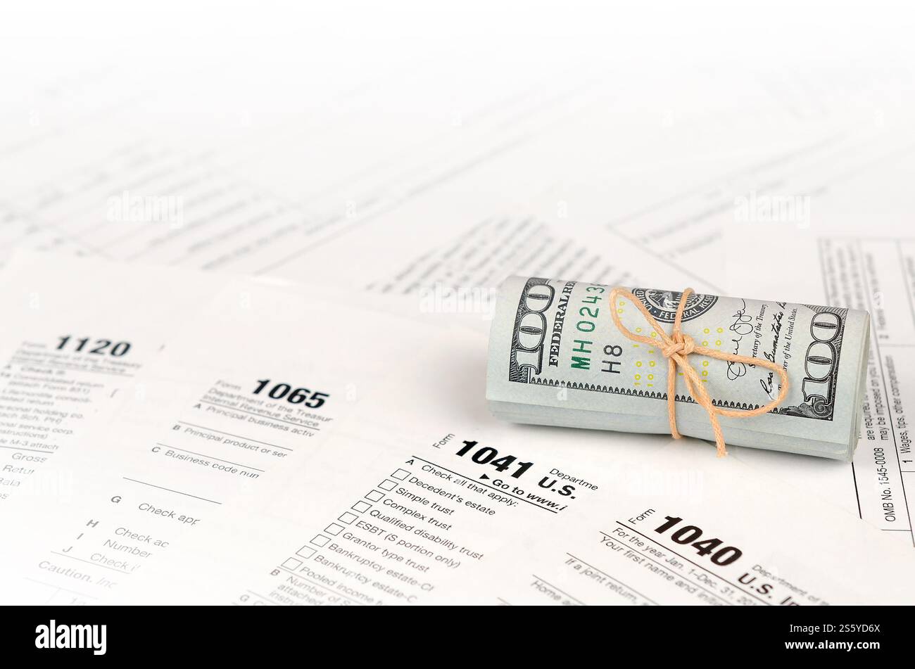 Tax forms lies near roll of hundred dollar bills. Income tax return ...