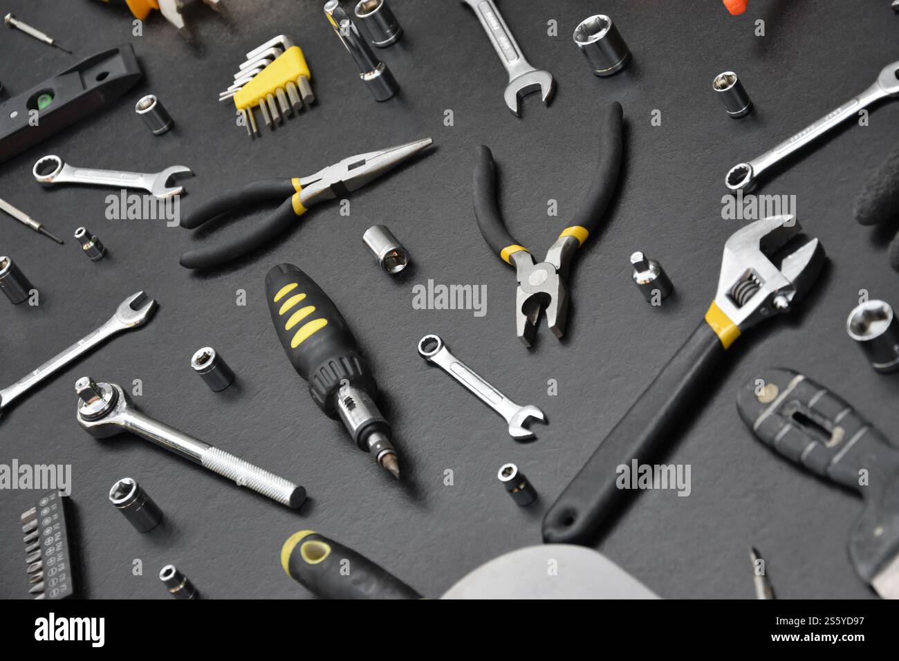 Handyman tool kit on black wooden table. Many wrenches and screwdrivers ...