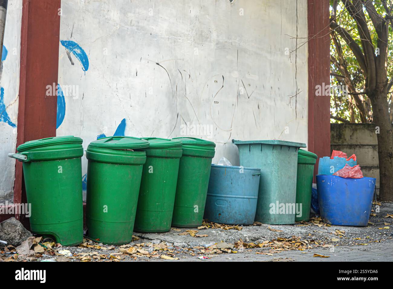 some green trash cans lining the roadside next to a building Stock ...