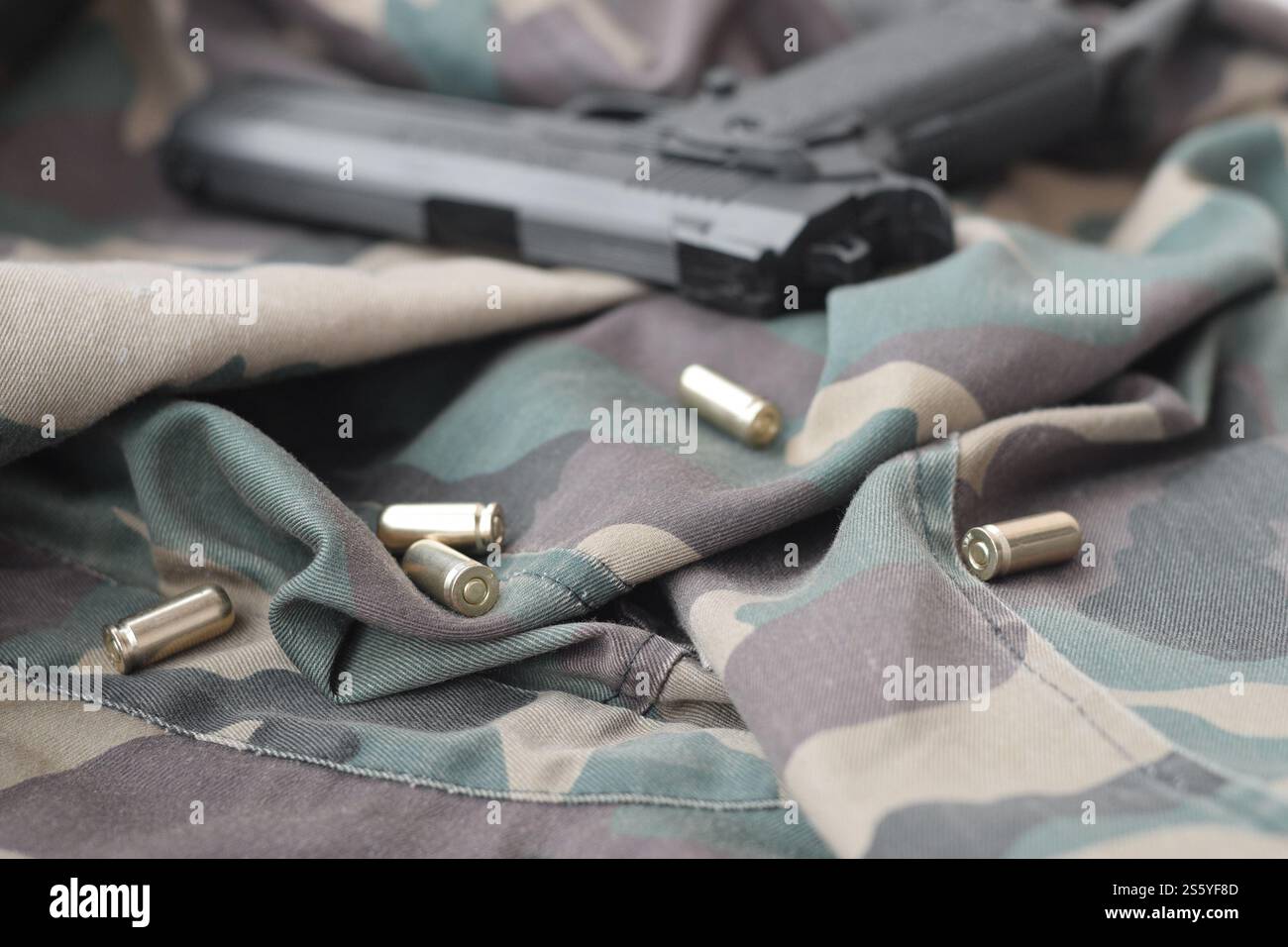 9mm bullets and pistol lie on folded camouflage green fabric. A set ...