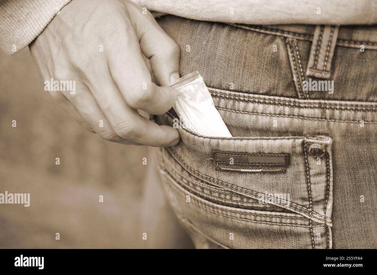 Male hand retrieving drug packet our of blue jean pocket with copy ...
