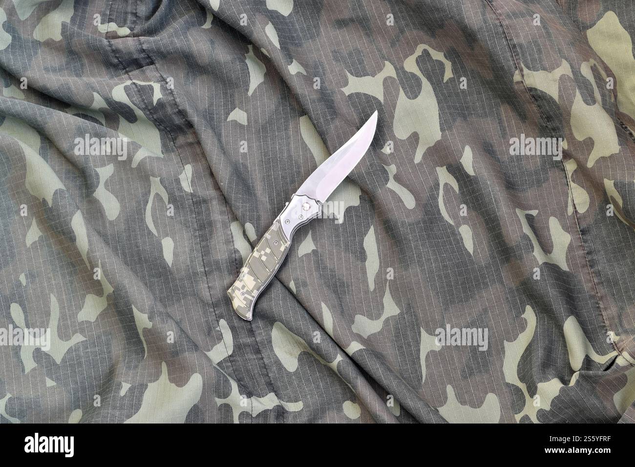 Military knife on army camouflage clothes close up. Background with ...