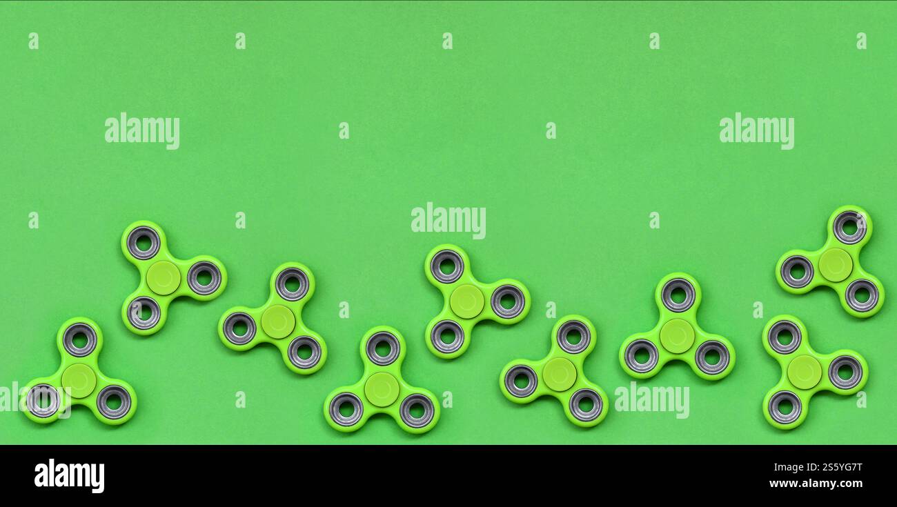 Many green fidget spinners lies on texture background of fashion pastel ...