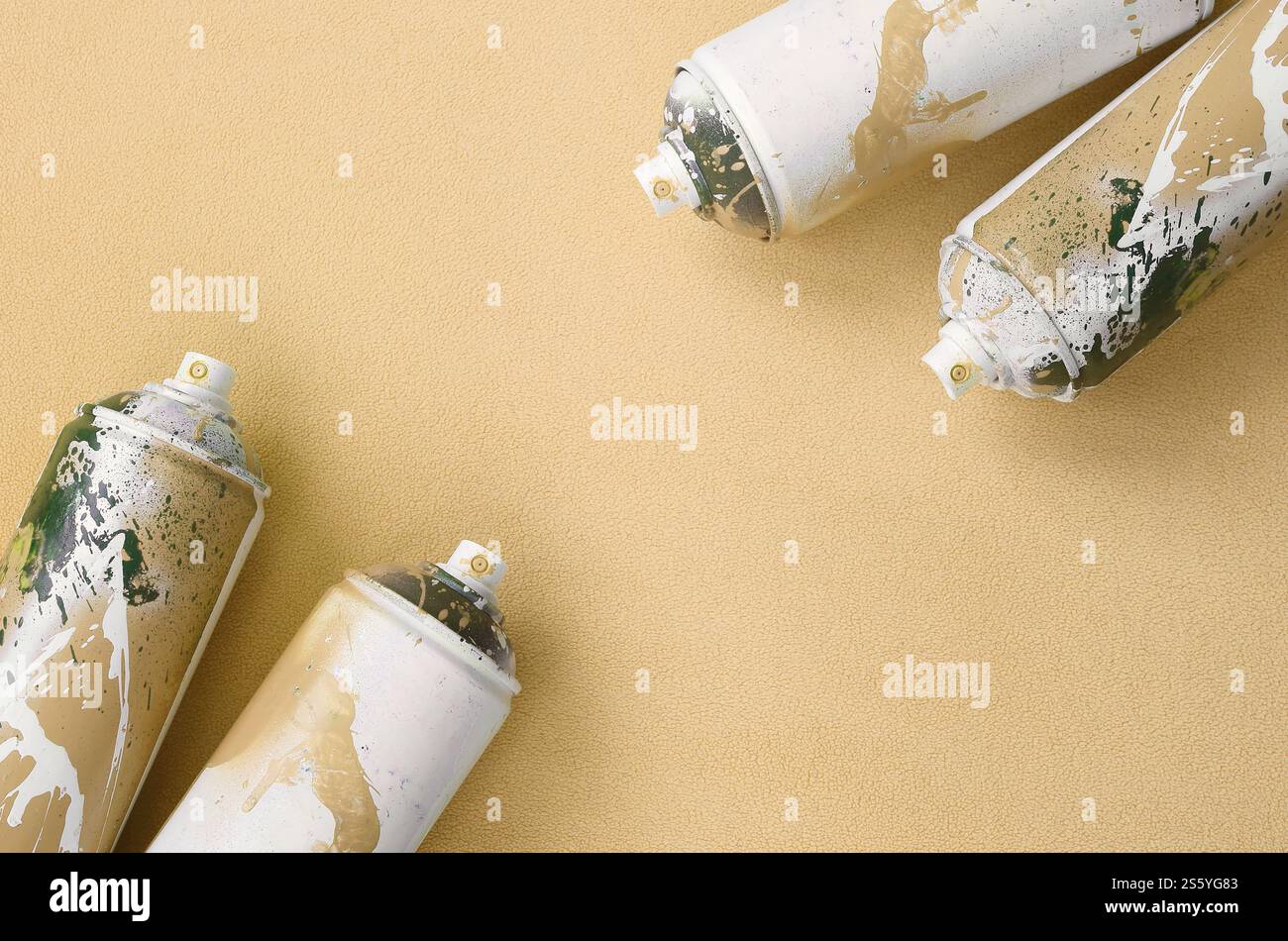 Some used blue aerosol spray cans with paint drips lies on a blanket of ...