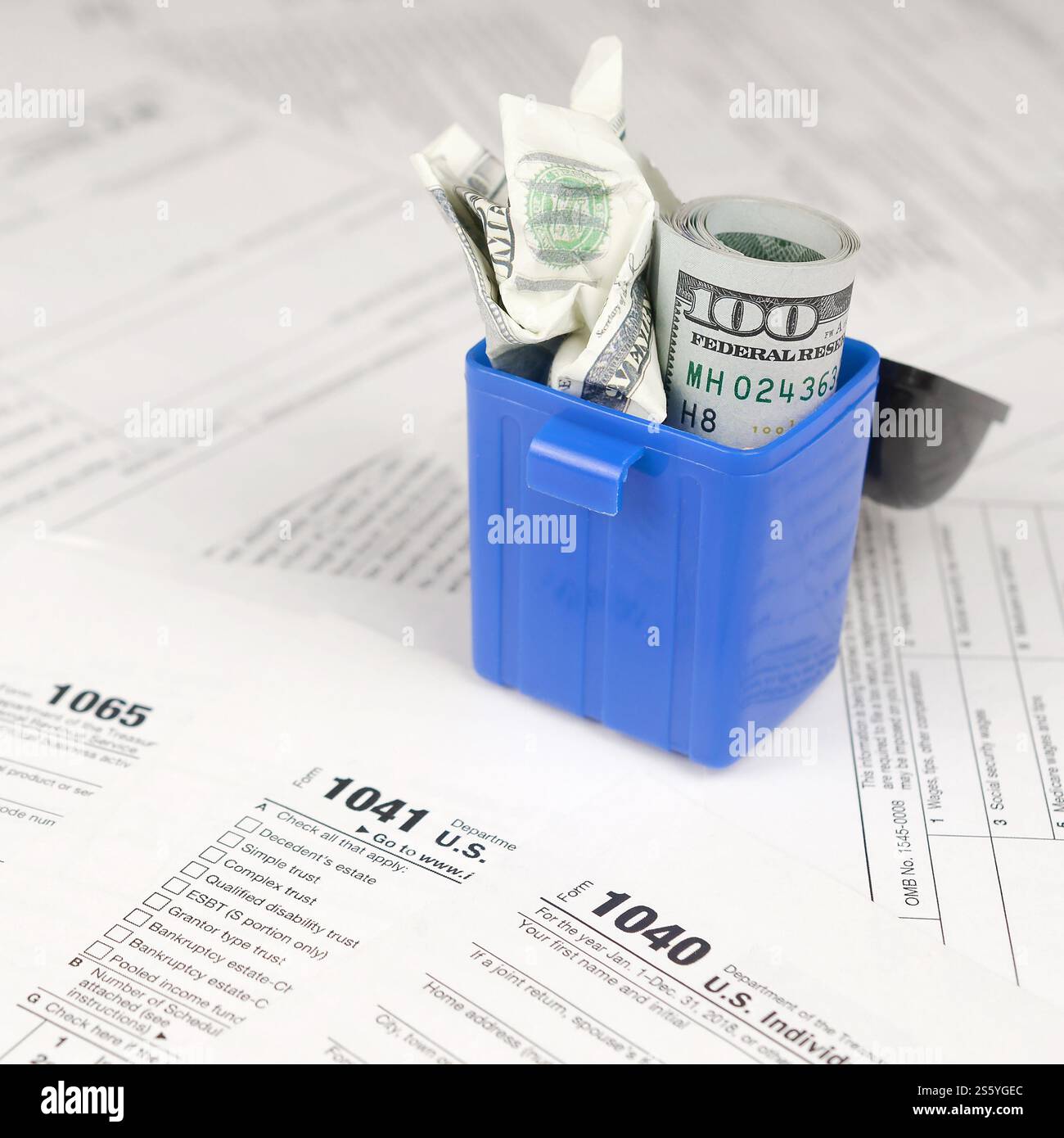 Many american tax blank forms and crumpled hundred dollar bill in trash ...