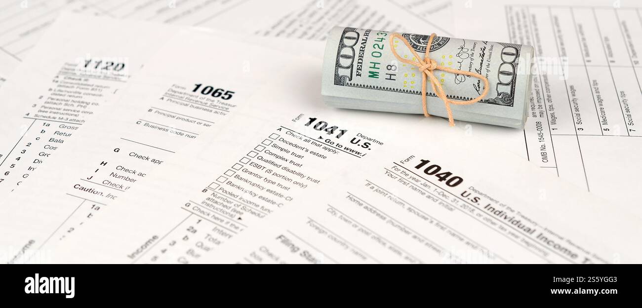 Tax forms lies near roll of hundred dollar bills. Income tax return ...
