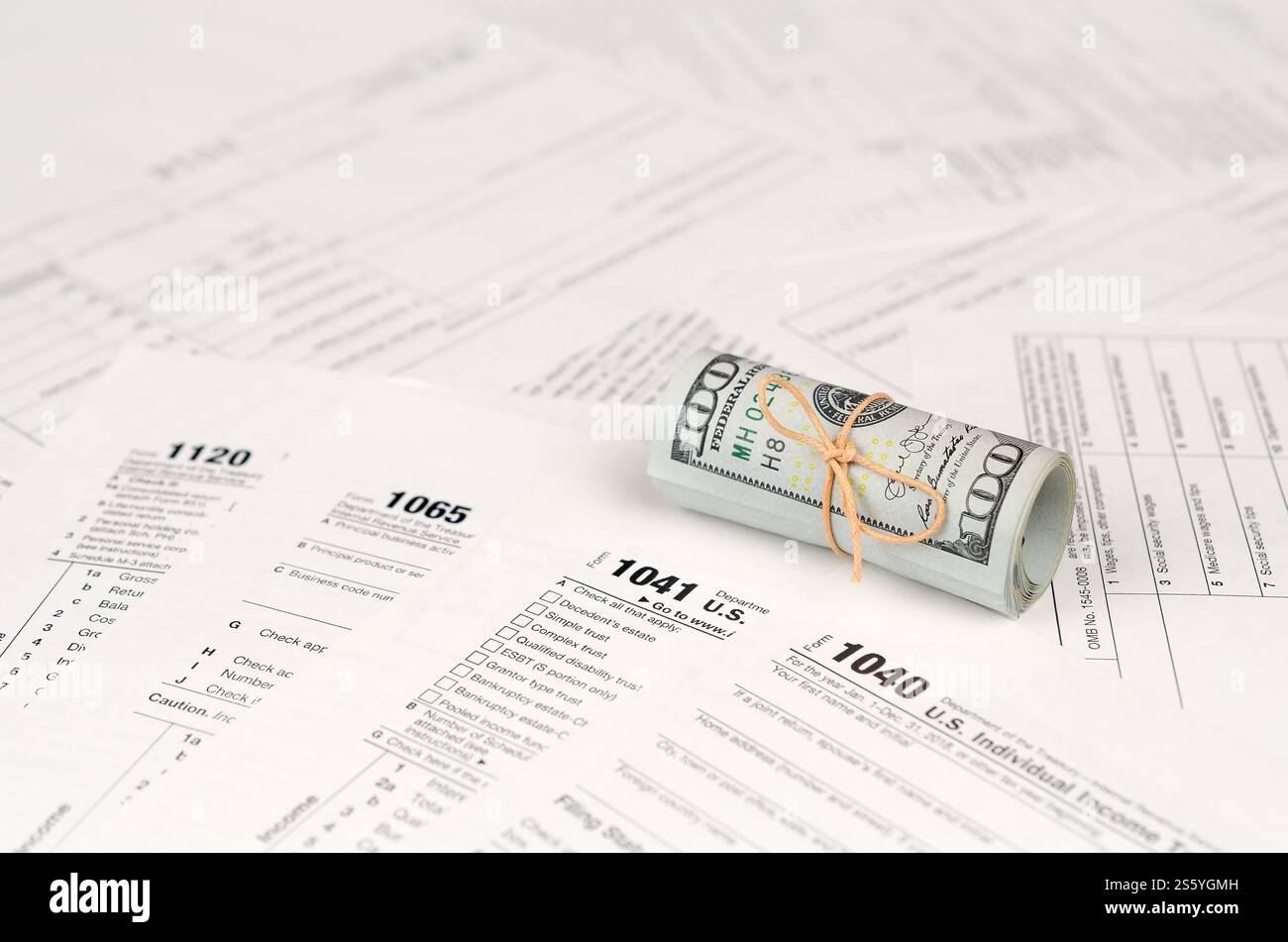 Tax forms lies near roll of hundred dollar bills. Income tax return ...