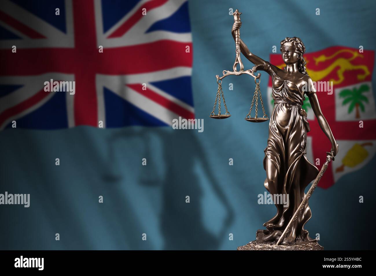 Fiji flag with statue of lady justice and judicial scales in dark room ...