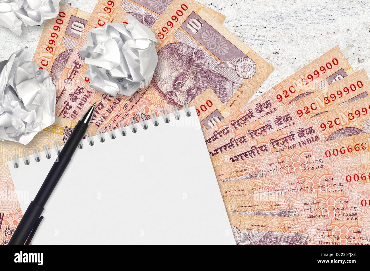 10 Indian rupees bills and balls of crumpled paper with notepad. Bad ...