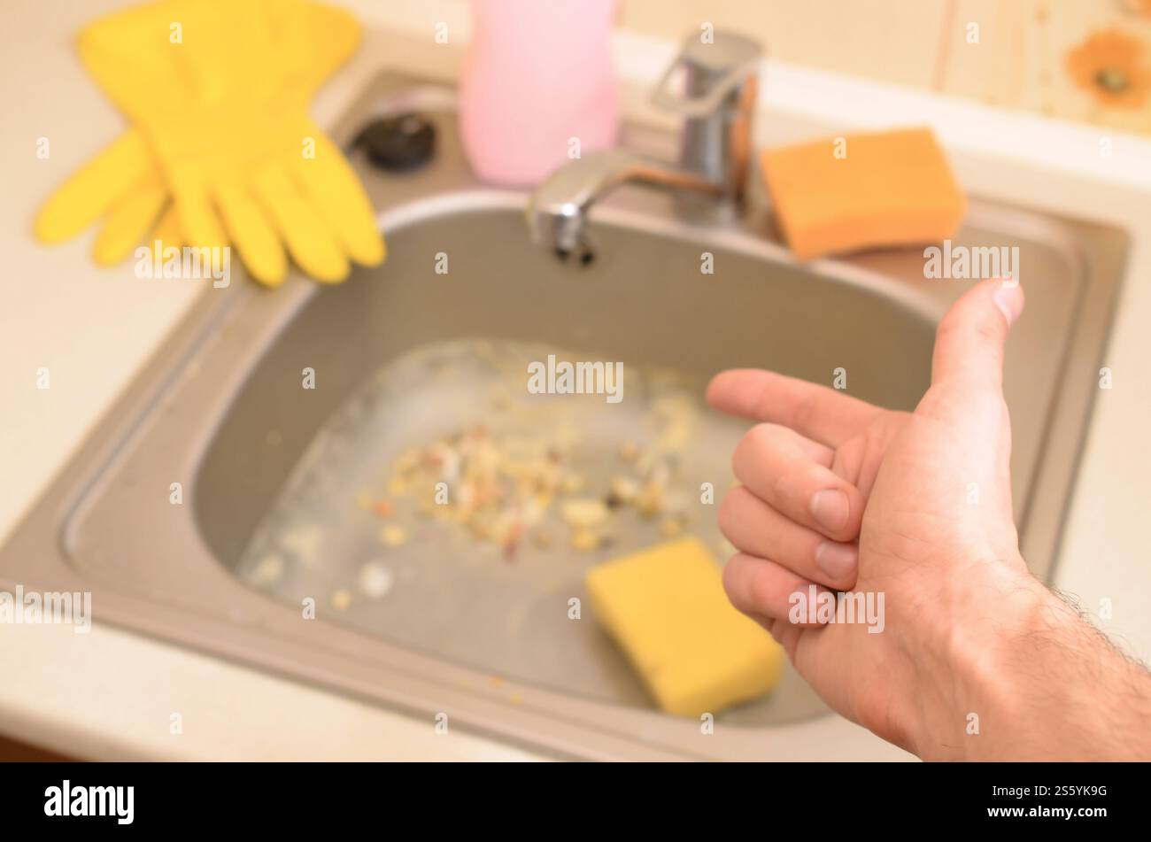 Hand points to dirty kitchen sink with many food particles before the ...