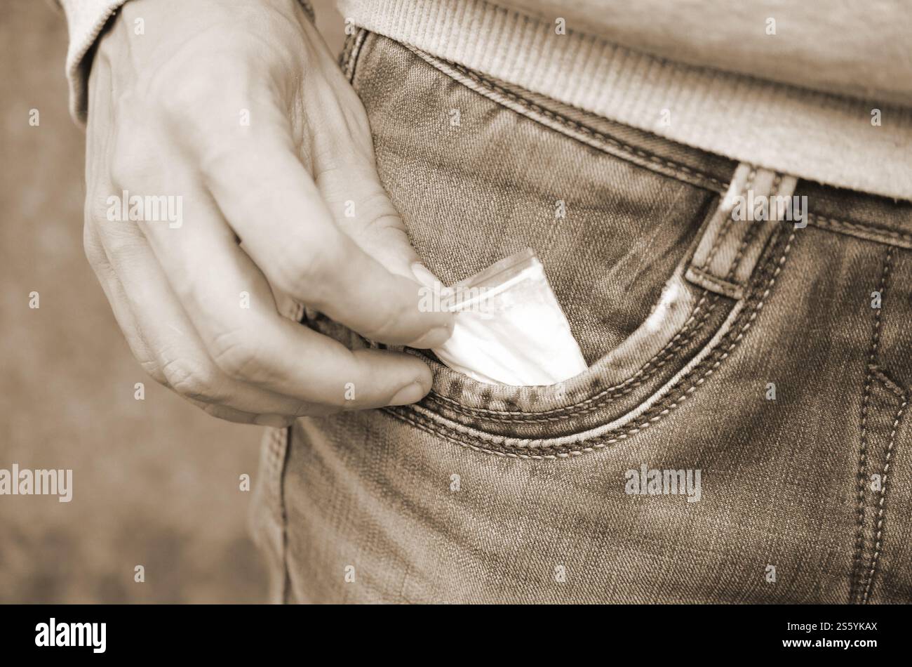 Male hand retrieving drug packet our of blue jean pocket with copy ...