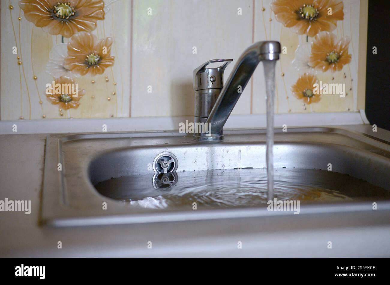 Stainless steel sink plug hole close up full of water and particles of ...