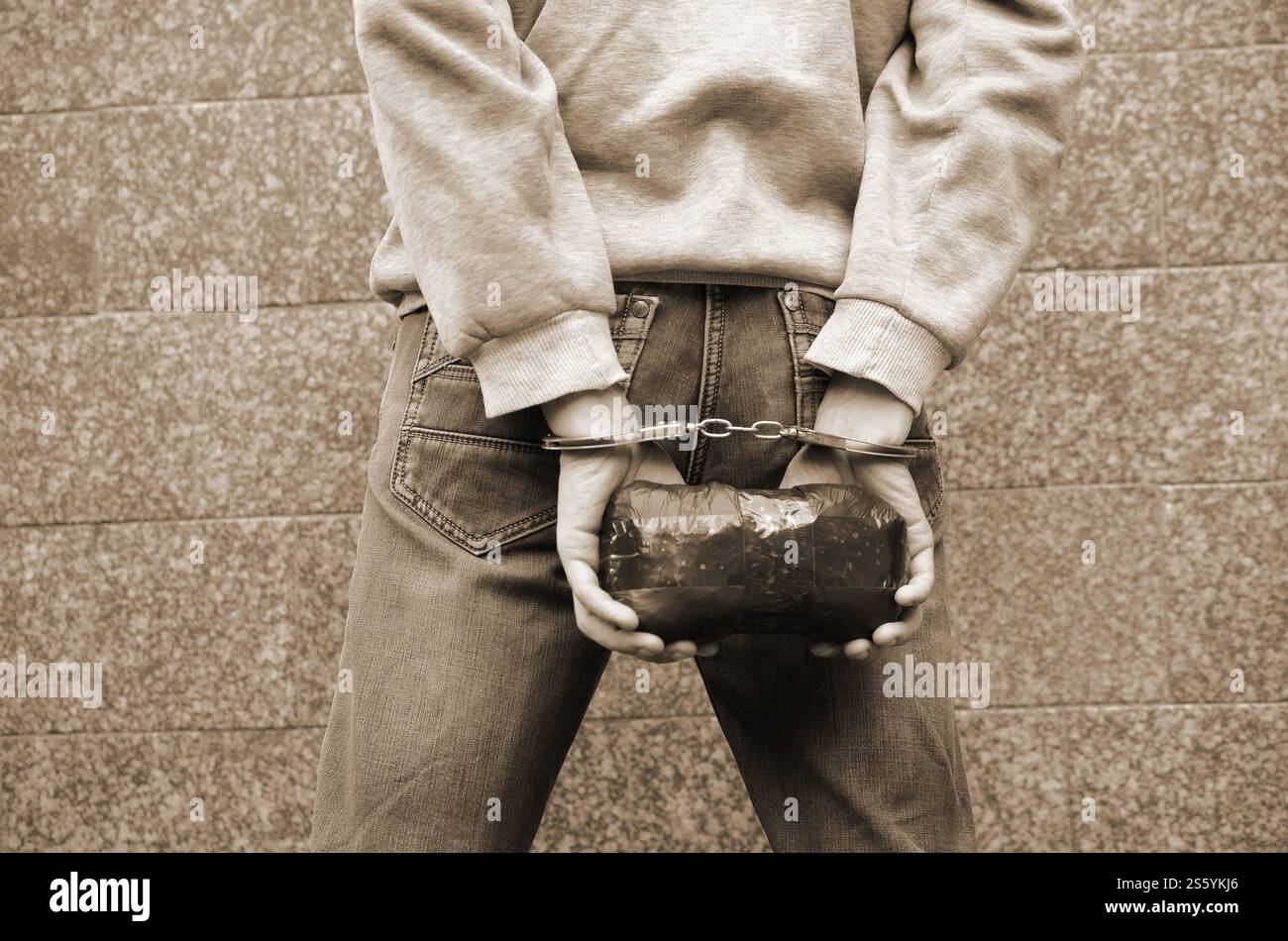 Arrested drug dealer in handcuffs with big heroin drug package on dark ...